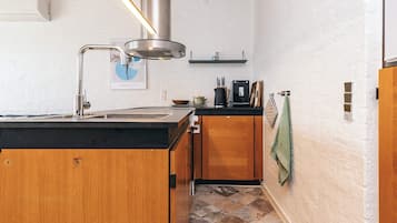 Uma cozinha moderna com exaustor de aço inoxidável, armários de madeira, bancada preta e piso ladrilhado.