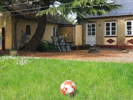 Uma casa com gramado, árvore e móveis de jardim.