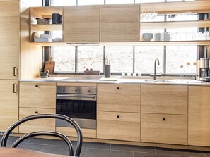 Uma cozinha moderna com armários de madeira, uma pia de aço inoxidável e um forno embutido.