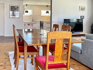 Uma área de refeições com uma mesa e cadeiras de madeira, uma televisão e um sofá.