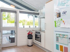 Cozinha moderna com forno embutido, lixeira de aço inoxidável e geladeira com papéis e ímãs.