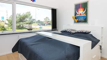 Quarto com cama, janela, radiador e pôster na parede.