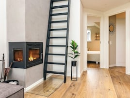 Quarto com lareira, piso de madeira, escada e uma planta.