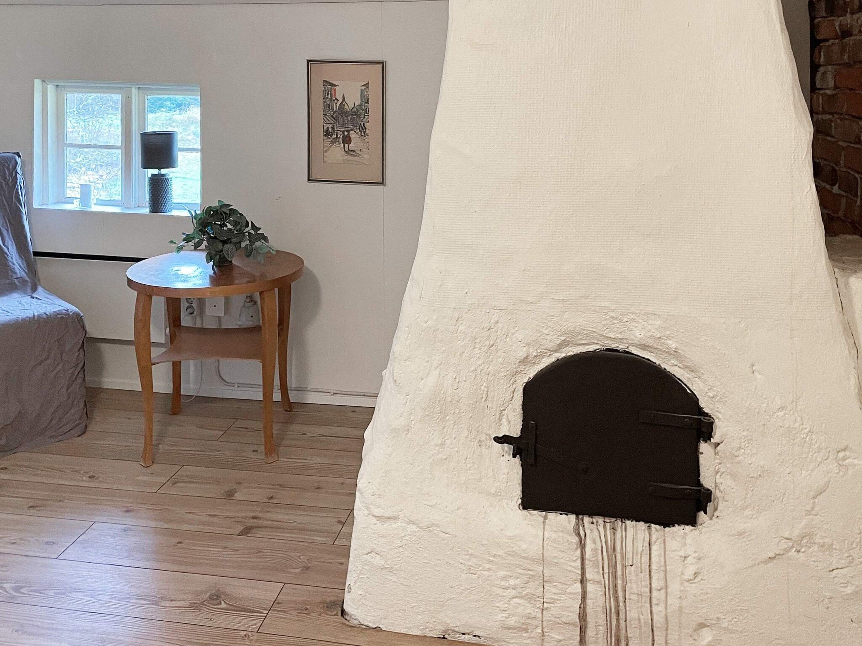 Quarto com parede branca texturizada, mesa de madeira com uma planta e janela com vista.