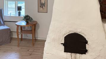 Quarto com parede branca texturizada, mesa de madeira com uma planta e janela com vista.
