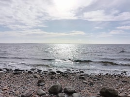 Uma praia rochosa com ondas quebrando na costa sob um céu parcialmente nublado.