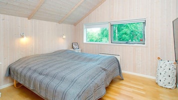 Quarto com cama, duas janelas, mesa de cabeceira e luminária na parede.