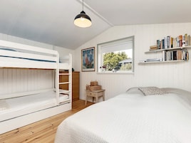 Quarto com beliche, janela, estante e escrivaninha.