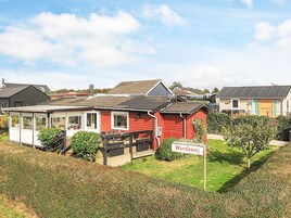 Uma casa de madeira vermelha com uma placa indicando 'Wondasvej' em uma área residencial com outras casas.