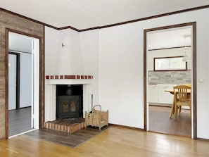 Quarto com lareira, área de cozinha com armários e janela, e piso de madeira.