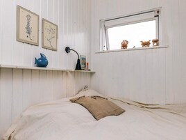 Quarto com uma cama, uma janela e duas prateleiras fixadas na parede com objetos decorativos.