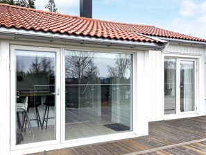 Uma casa moderna com telhado cerâmico, amplas portas de correr de vidro e um deck de madeira.