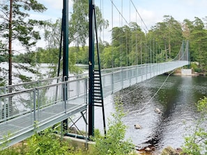 Ponte suspensa sobre um rio, com guarda-corpos e passarela de metal.