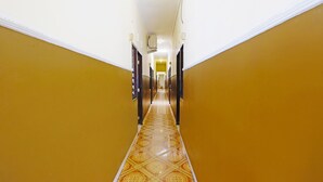 Um corredor com chão estampado e paredes amarelas.