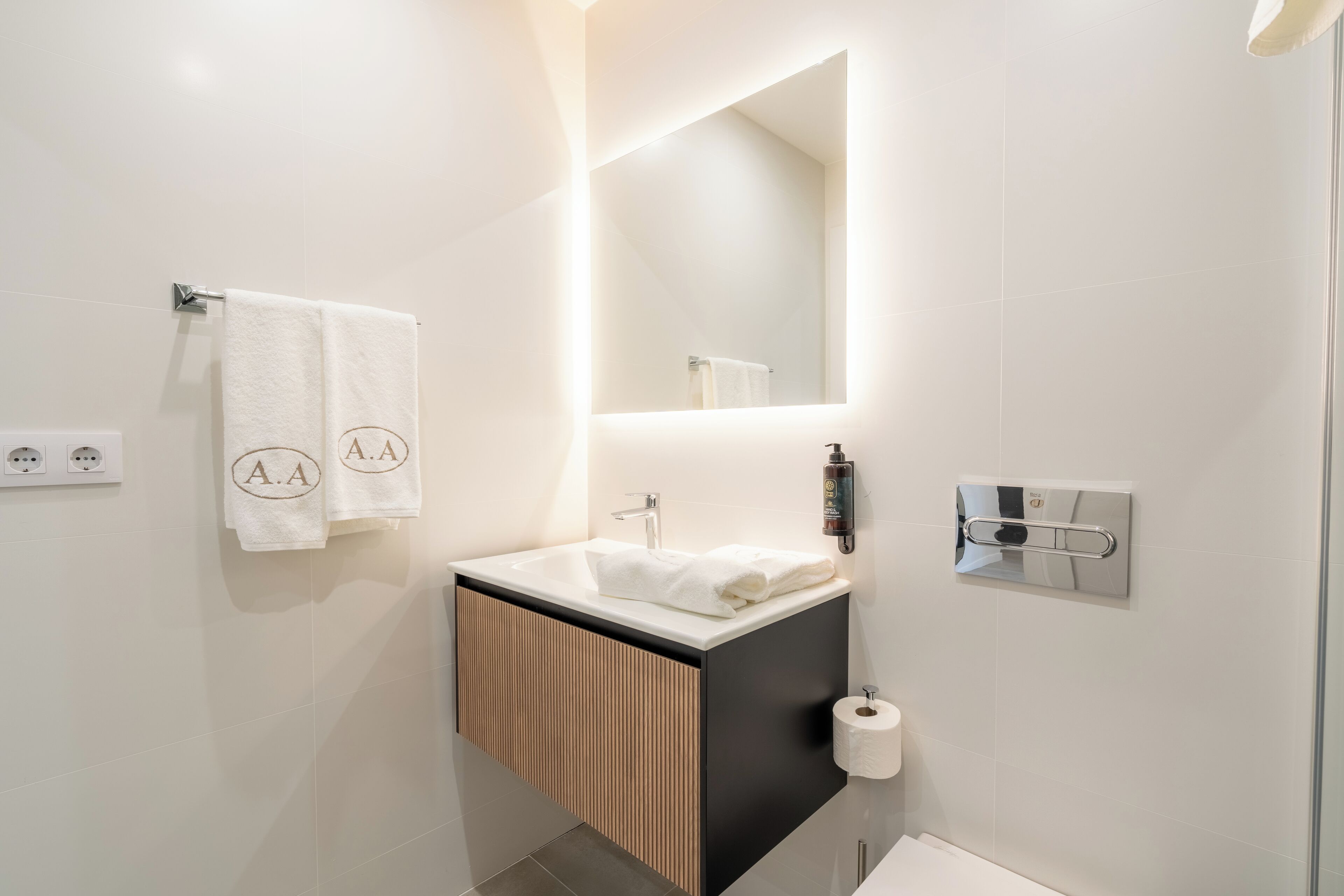 Uma casa de banho moderna com uma pia branca, um espelho e um porta-toalhas com toalhas.