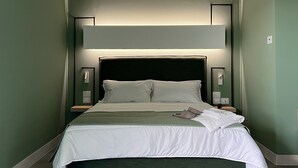 Quarto moderno com uma cama grande, duas mesas de cabeceira e iluminação embutida na parede.