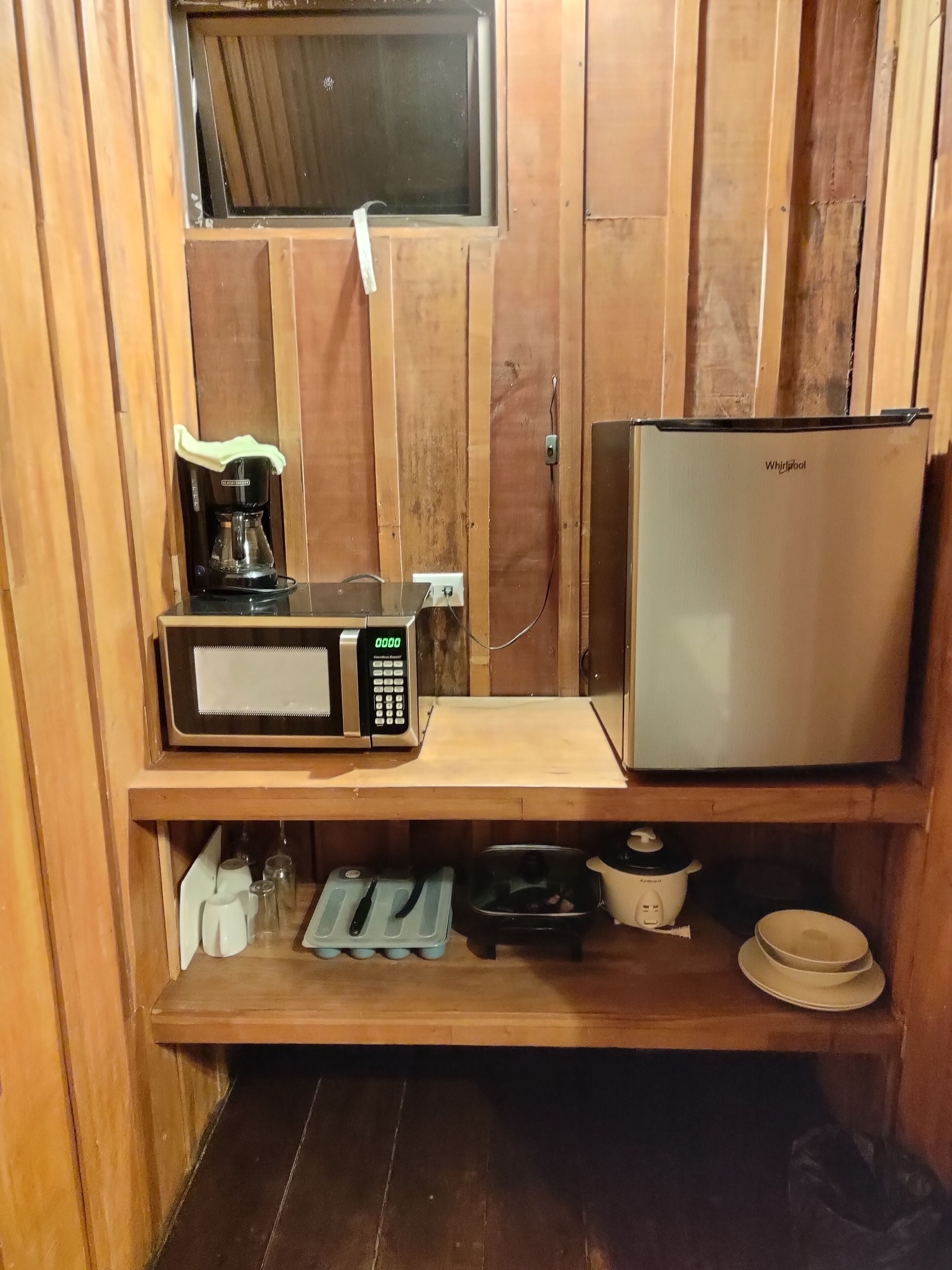 Uma cozinha compacta equipada com micro-ondas, cafeteira e geladeira.