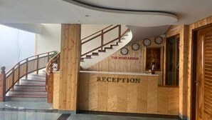 Uma receção com design em madeira, uma escadaria e relógios na parede.