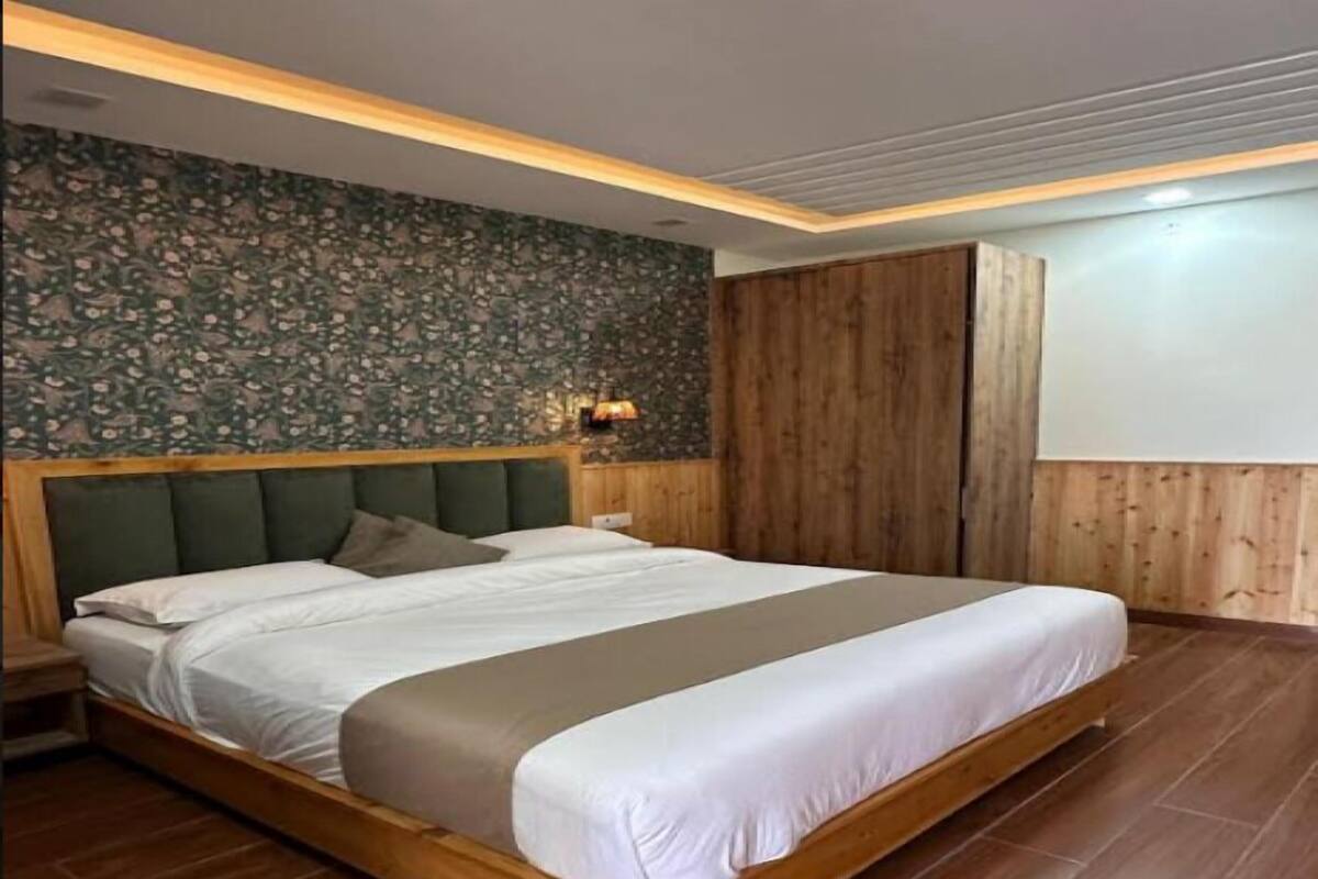 Uma cama grande com estrutura de madeira e cabeceira verde, parede com padrão de pedra e um guarda-roupa de madeira.