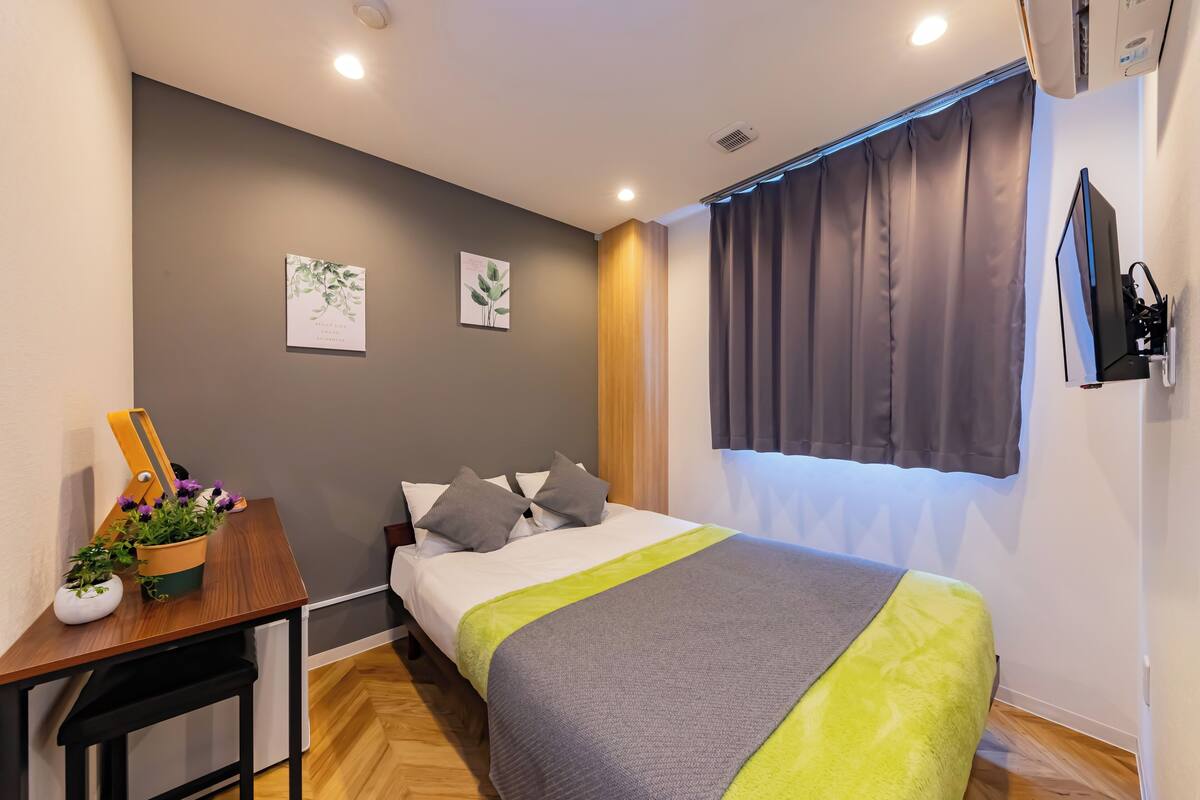 Quarto moderno com cama, mesa de cabeceira e janela com cortinas.