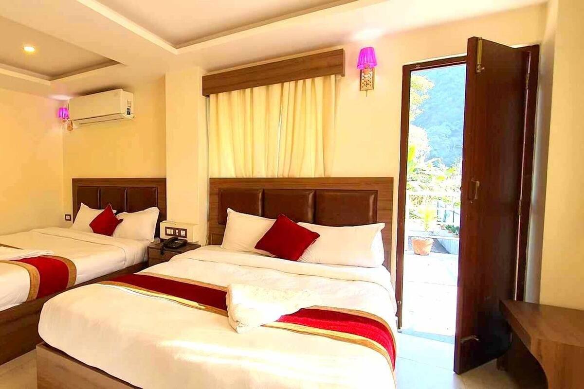 Quarto de hotel com duas camas, ventilador de teto, ar condicionado e vista para o exterior.