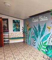 Quarto com um banco, um mural na parede e um suporte para sapatos.