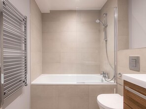 Uma casa de banho moderna com banheira, chuveiro e sanita.