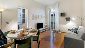 Uma sala de estar moderna com área de jantar, sofá, televisão e lareira.
