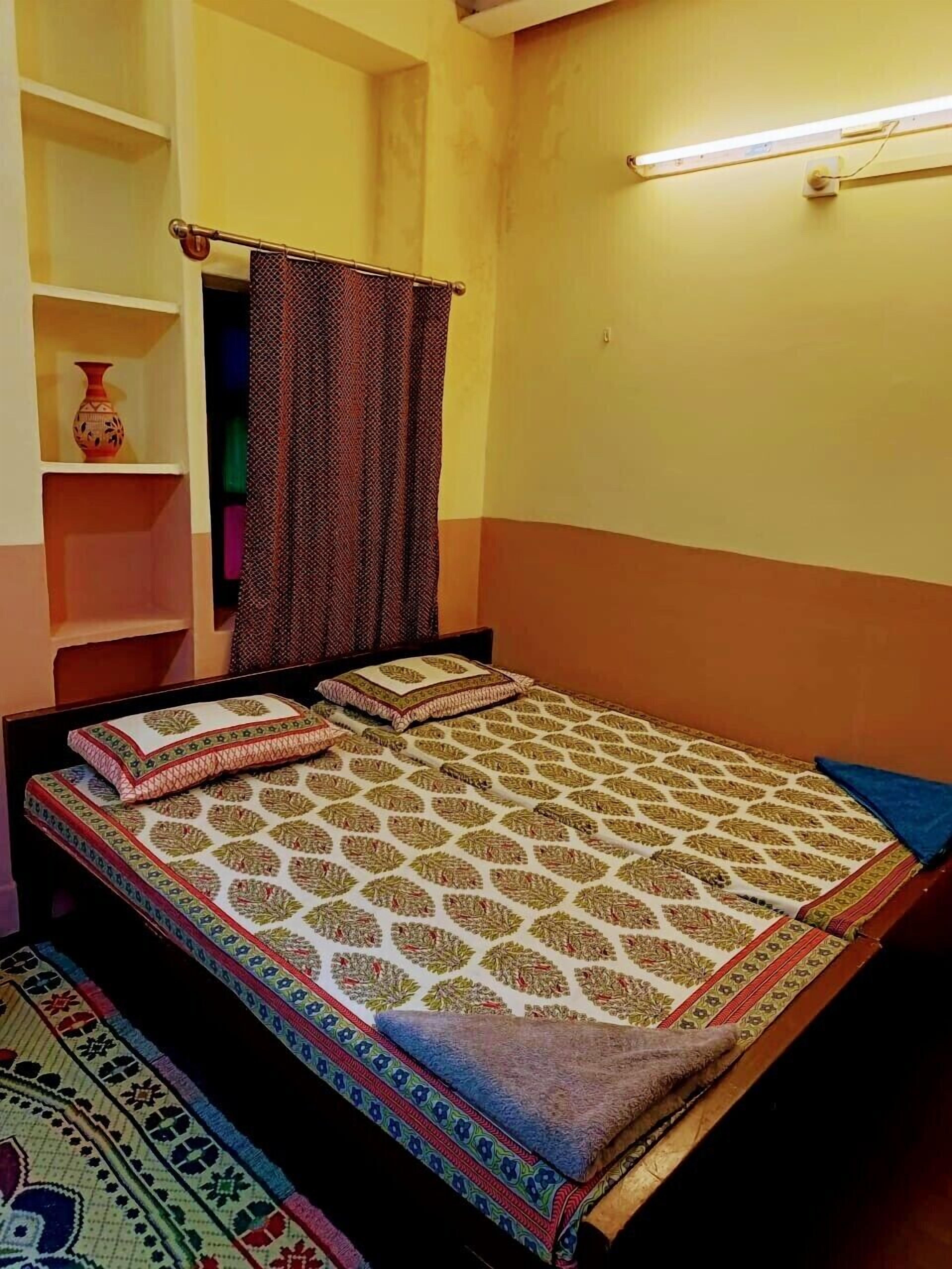 Quarto com uma cama, uma estante com um vaso e uma cortina.