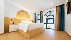 Quarto de hotel moderno com cama de madeira, mesa de cabeceira e uma janela grande com cortinas.