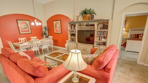 Uma sala de estar com sofá, mesa de centro, televisão e estante de livros.