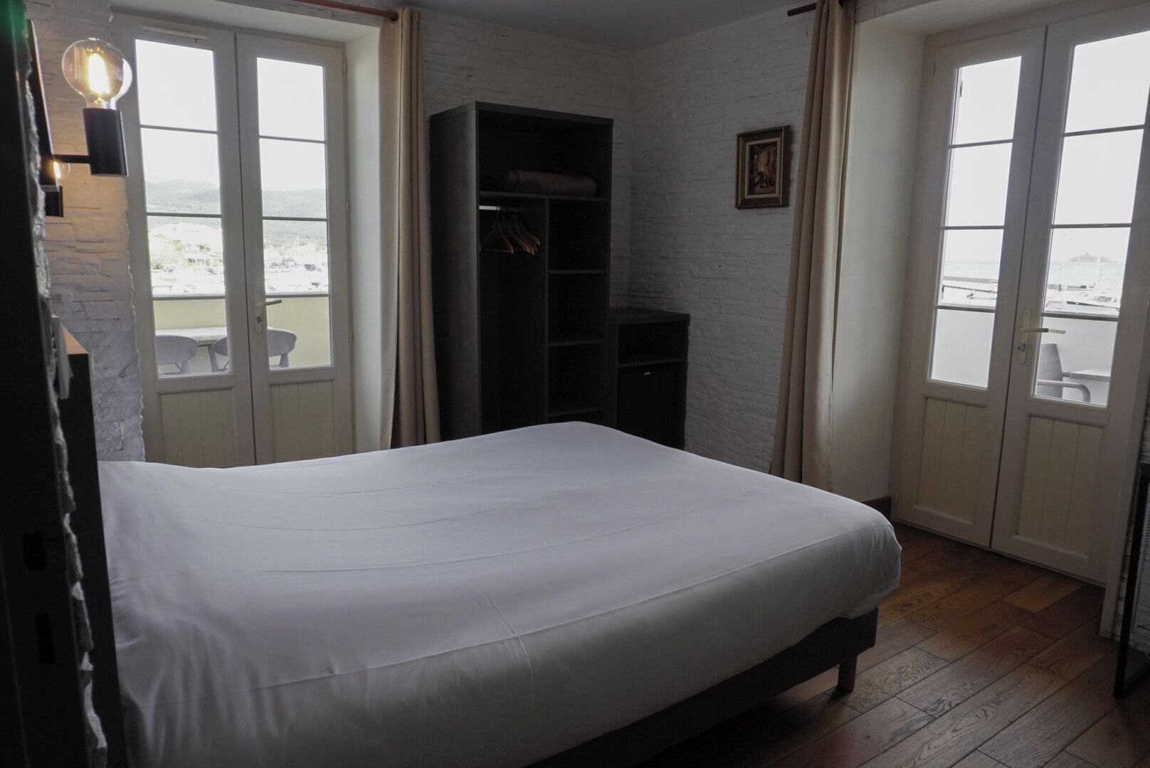 Quarto com cama, guarda-roupa e janela com cortinas.
