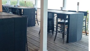 Pátio externo com móveis de vime e deck de madeira.