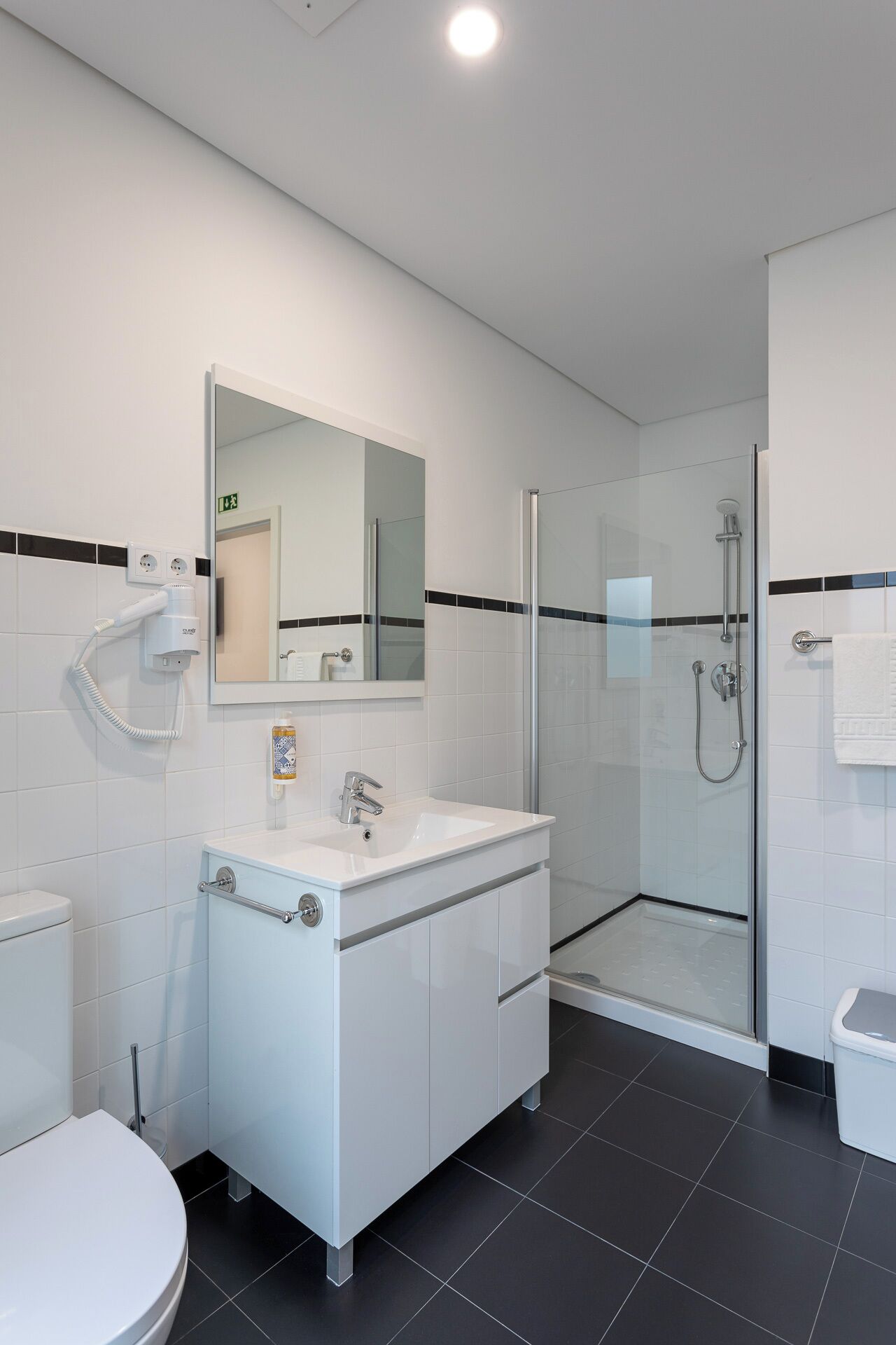Um banheiro moderno com toucador branco, box de vidro e vaso sanitário.