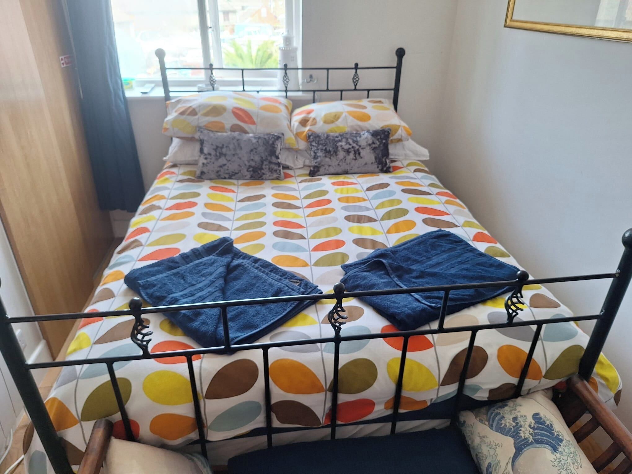 Cama com colcha de bolinhas, duas almofadas e um par de toalhas dobradas.