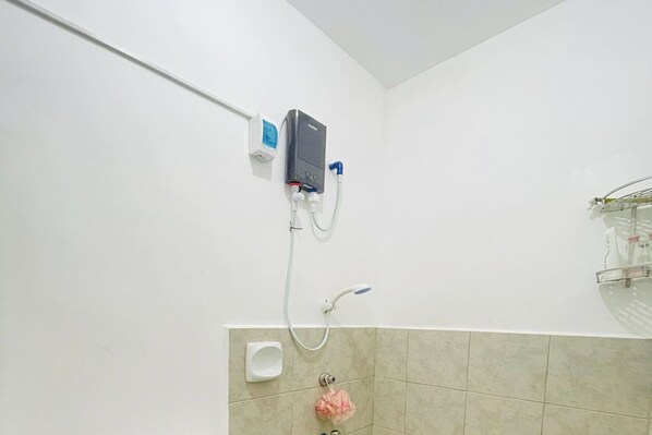 Casa de banho com chuveiro manual, dispensador de sabonete e porta-toalhas.