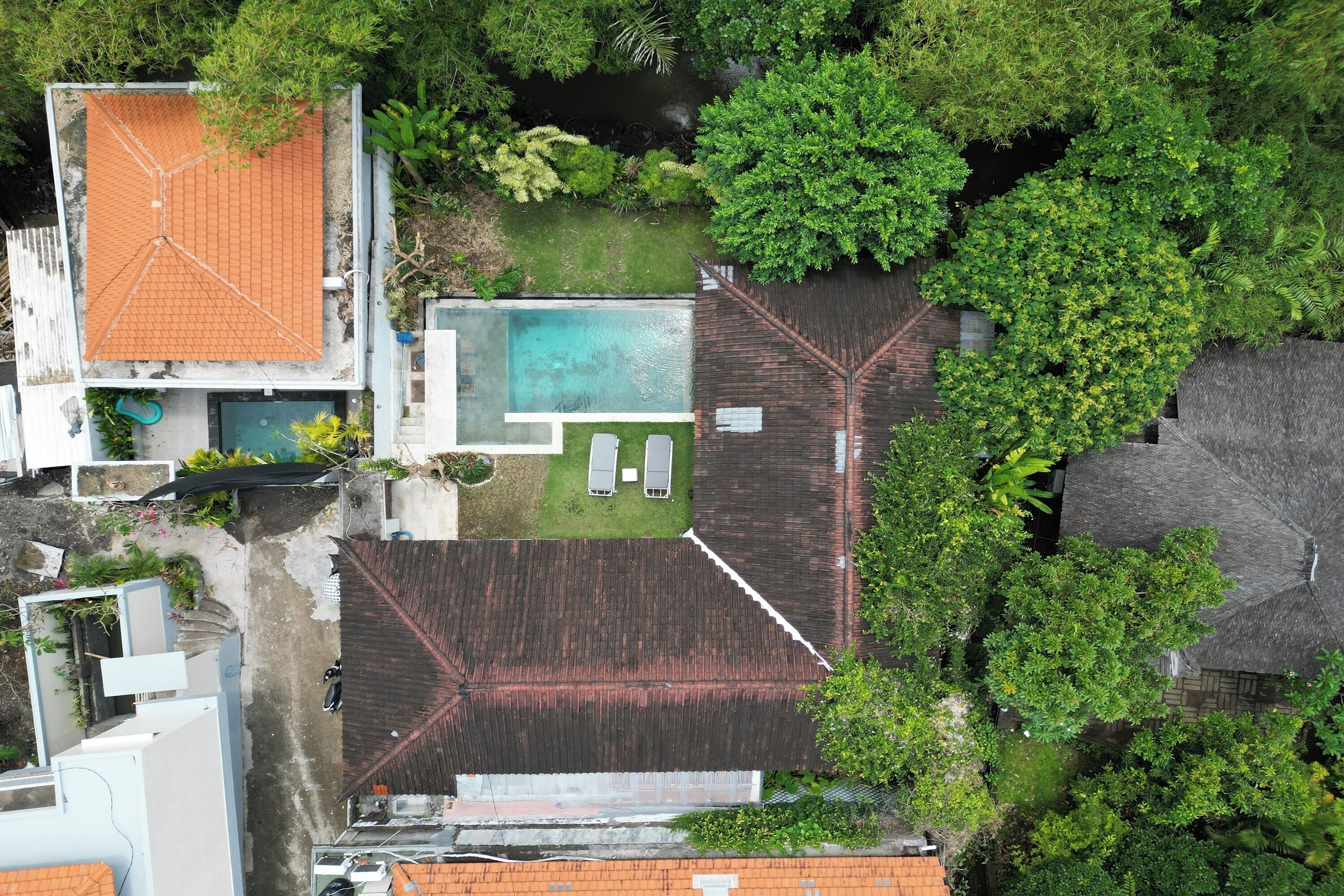 Vista aérea de uma propriedade residencial com piscina, quintal cercado e vegetação ao redor.