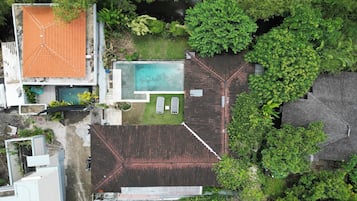 Vista aérea de uma propriedade residencial com piscina, quintal cercado e vegetação ao redor.