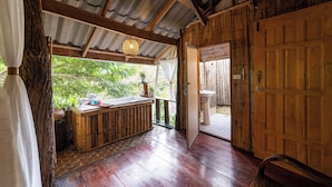 Uma cabana de madeira com interior rústico, incluindo um banco de madeira, uma pia pequena e uma mesa de madeira com toalhas.