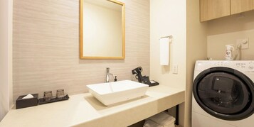 Casa de banho moderna com um espelho grande, uma sanita branca, uma máquina de lavar roupa preta e um porta-toalhas.