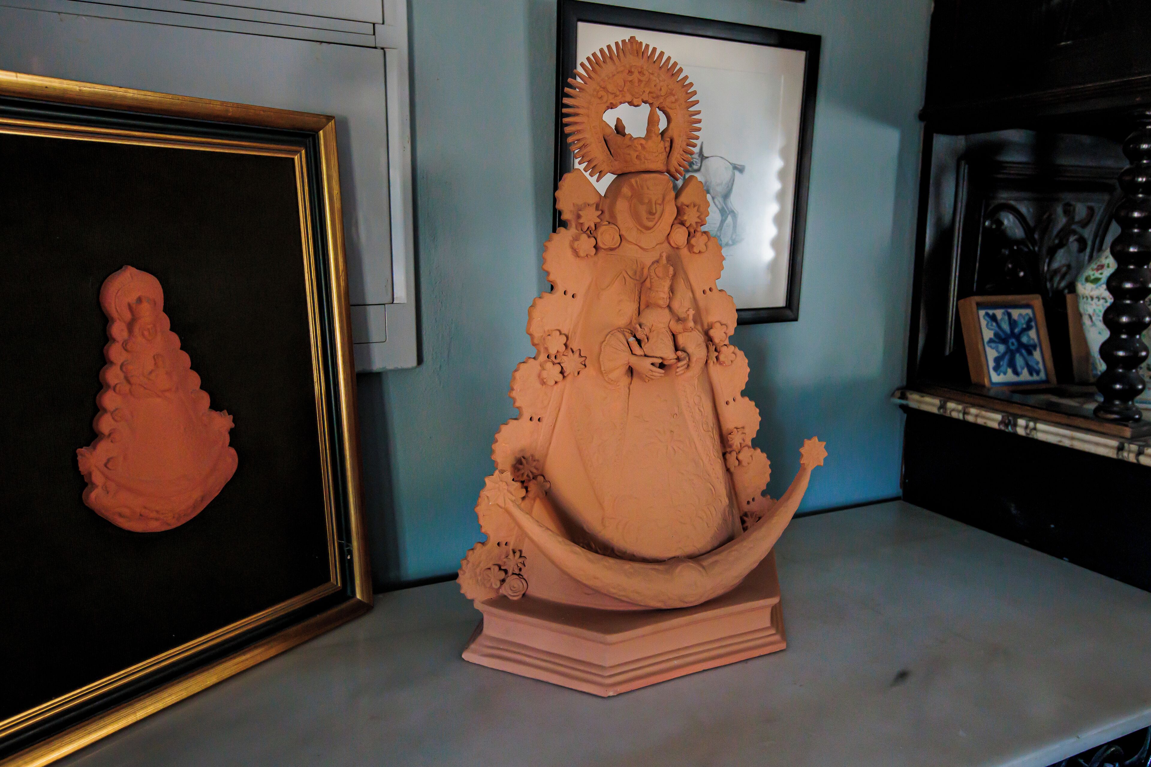 Escultura de uma figura com coroa e livro, colocada sobre um pedestal.