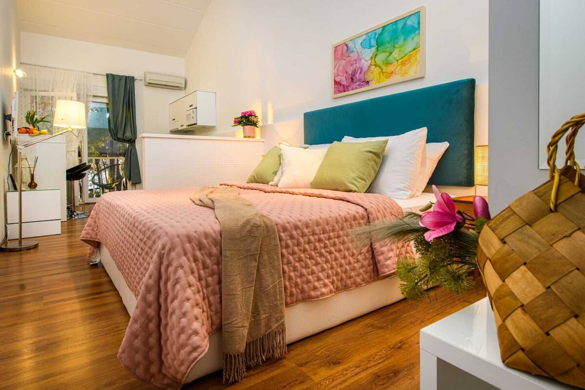 Quarto com cama, mesa de cabeceira, abajur e um quadro na parede.