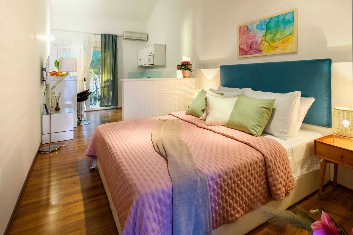 Quarto com cama, mesa de cabeceira e janela.