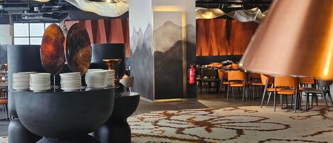 Interior de restaurante moderno com tetos altos, arte abstrata nas paredes e piso estampado.