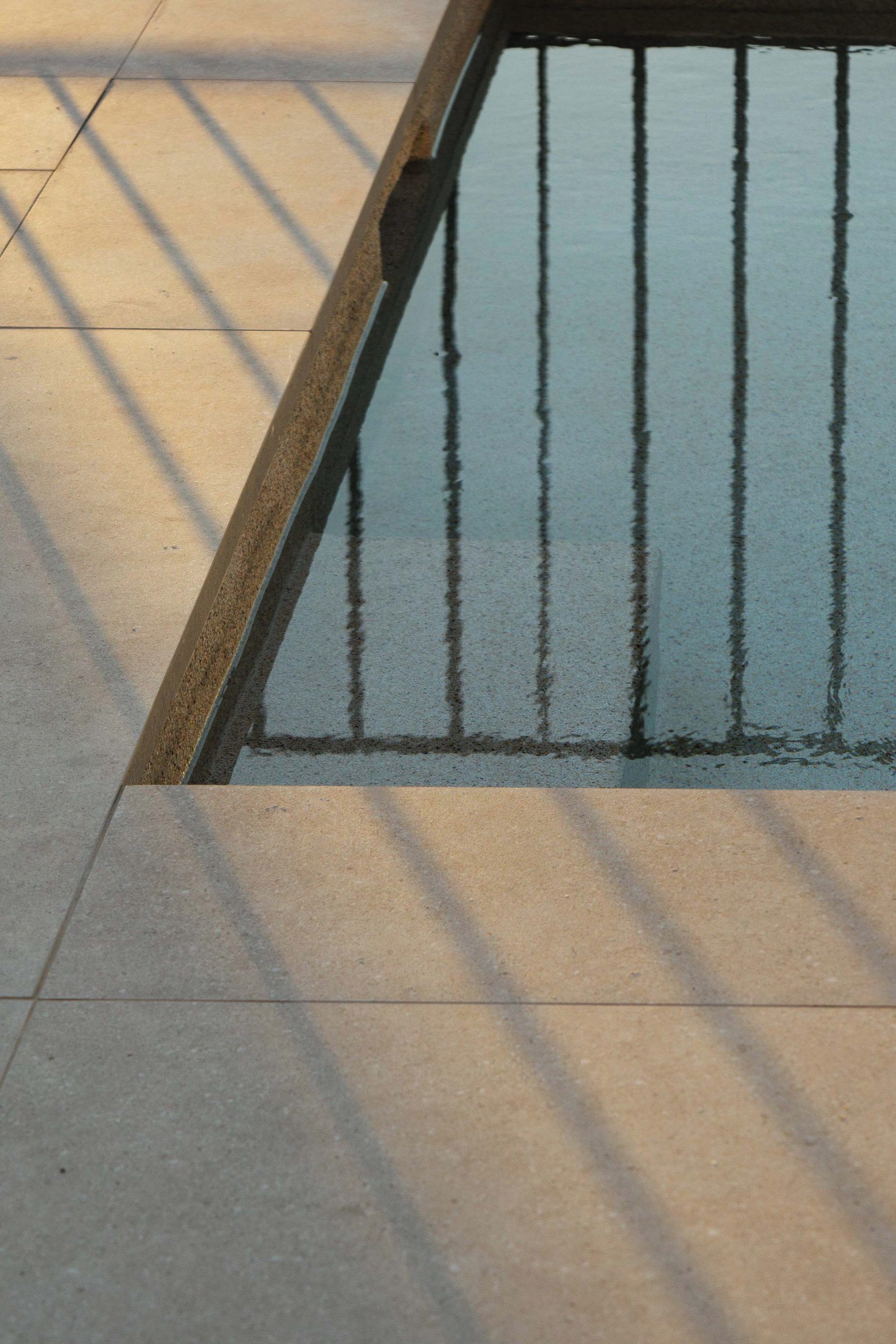 Piso de azulejos com uma grade de metal sobre uma superfície refletora.
