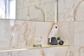 Um papagaio branco numa prateleira com uma vela e uma pequena planta.