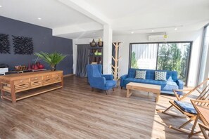 Uma sala de estar moderna com um sofá azul, uma mesa de centro de madeira e um espaço de refeições com cadeiras de madeira.