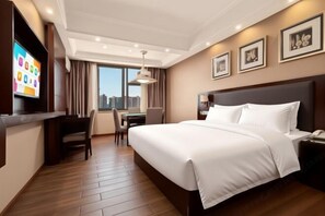 Quarto de hotel com uma cama grande, uma escrivaninha, uma cadeira, uma televisão e quadros nas paredes.