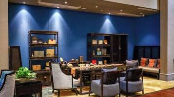 Um quarto com parede azul, piso de madeira, mesa de jantar com cadeiras e duas estantes com objetos.