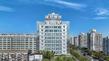 Um hotel imponente com vários andares, entrada destacada e vista ampla da paisagem urbana ao redor.